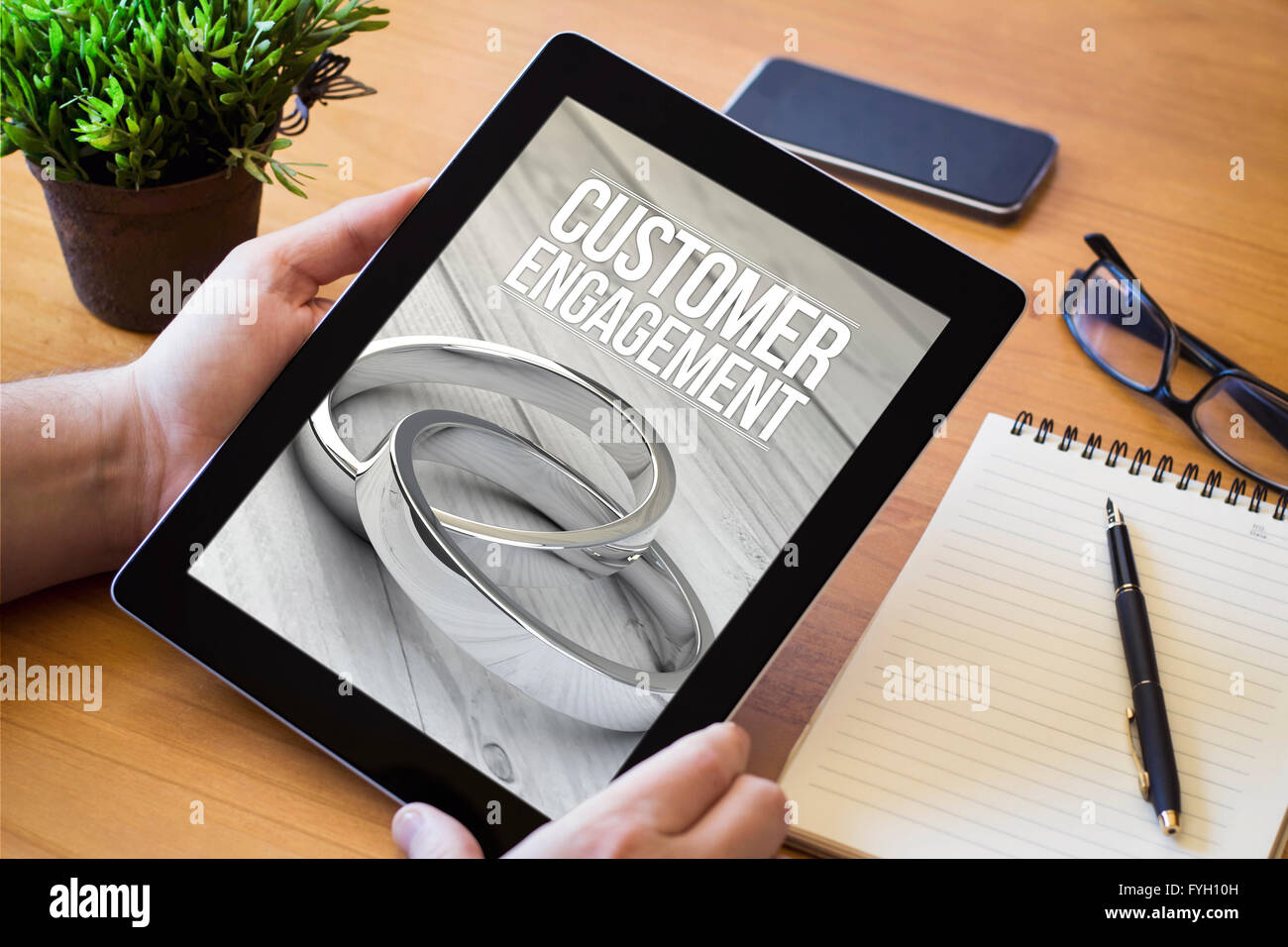 hands of a man holding a customer engagement device over a wooden ...