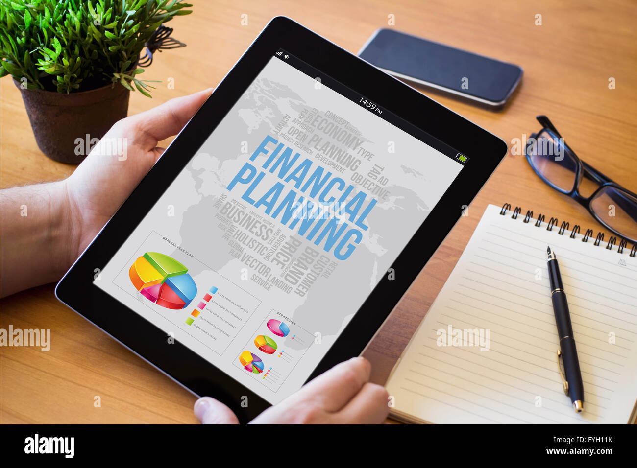 hands of a man holding a financial planning device over a wooden ...