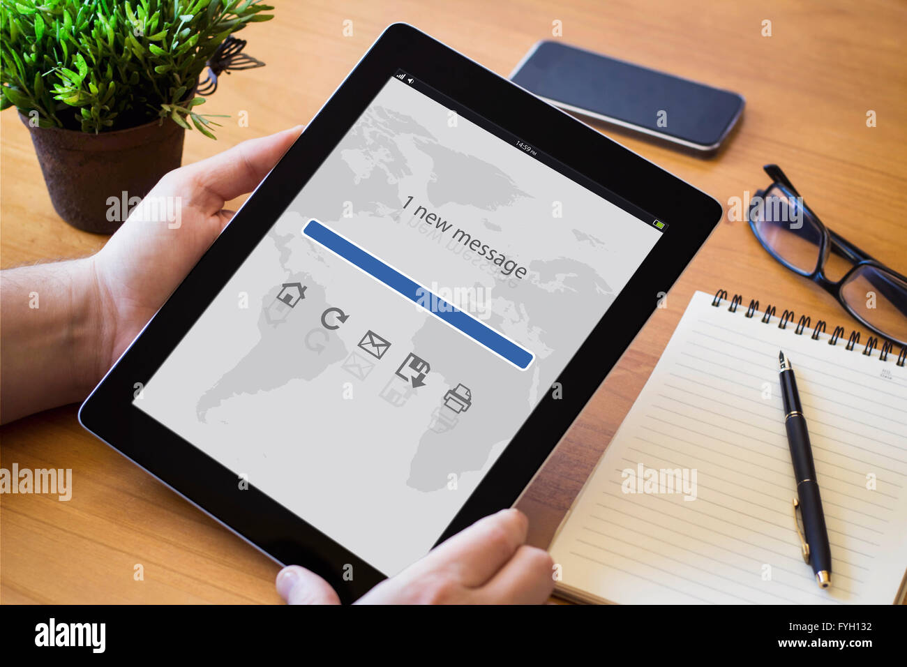 hands of a man holding a mail device over a wooden workspace table. All ...