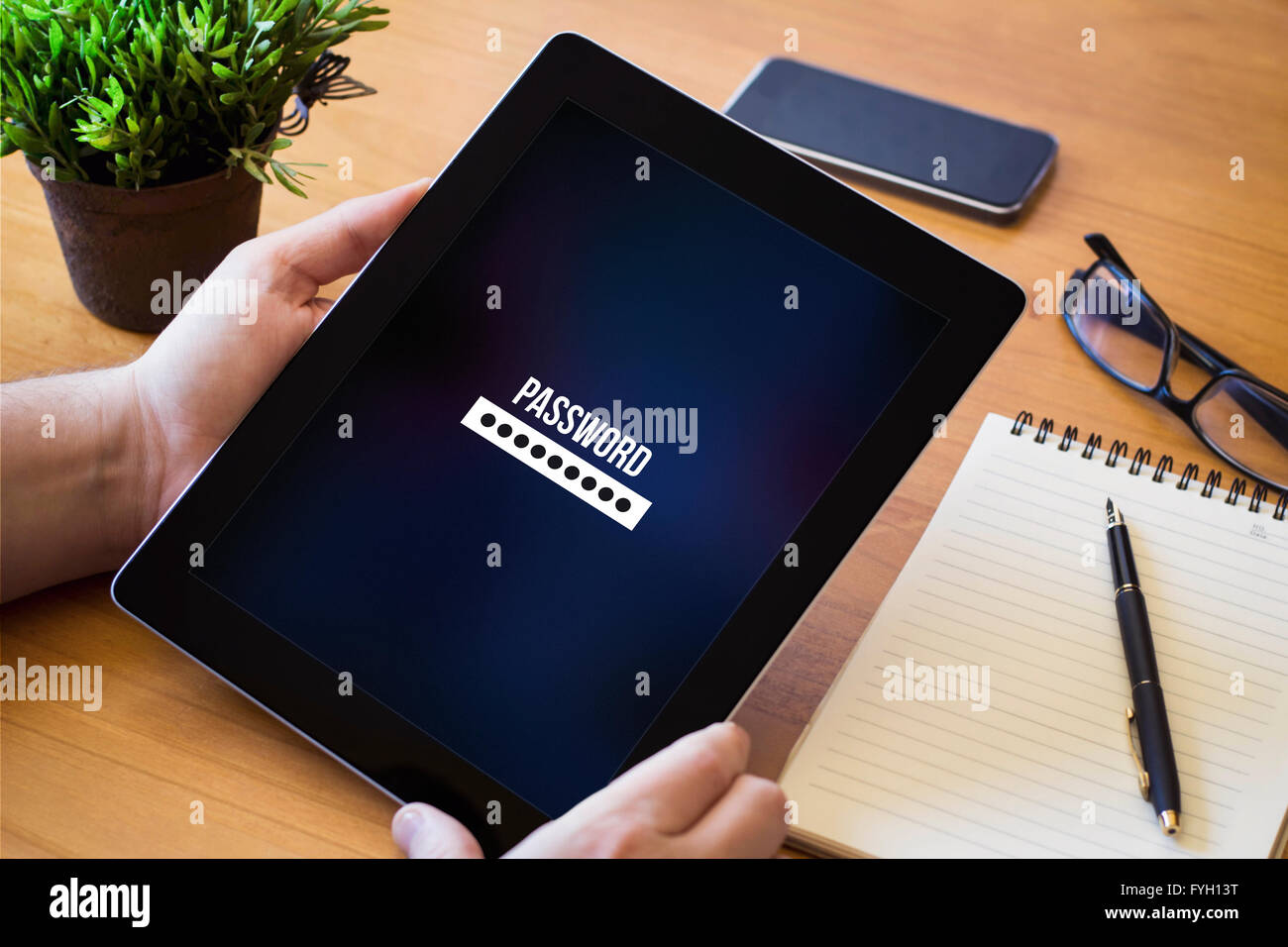 hands of a man holding a password device over a wooden workspace table ...
