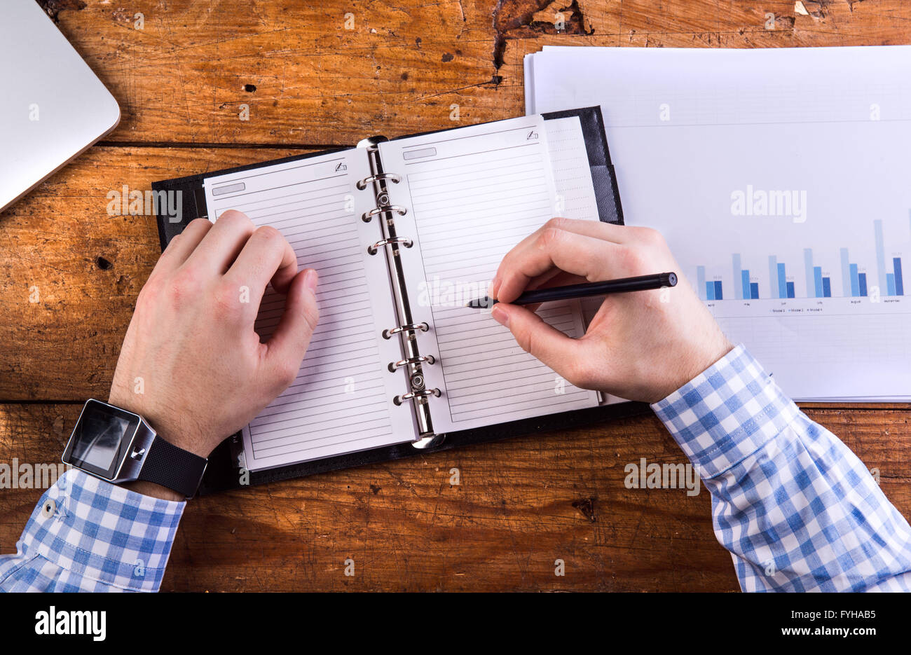 Businessman writing into personal organizer. Chart graph, wooden Stock ...