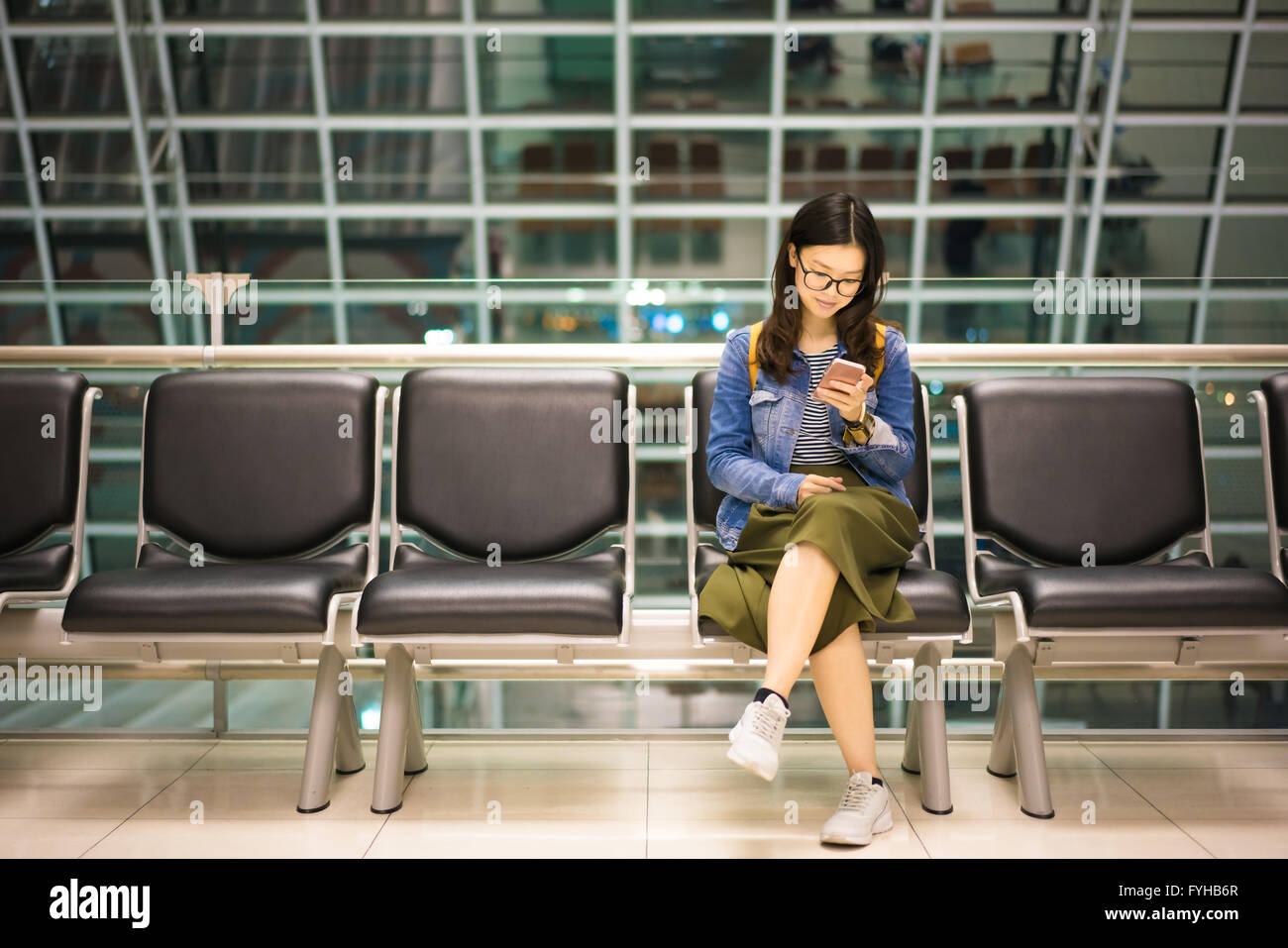 Beautiful Asian Girl Sitting Alone Smiling At Smartphone Waiting To