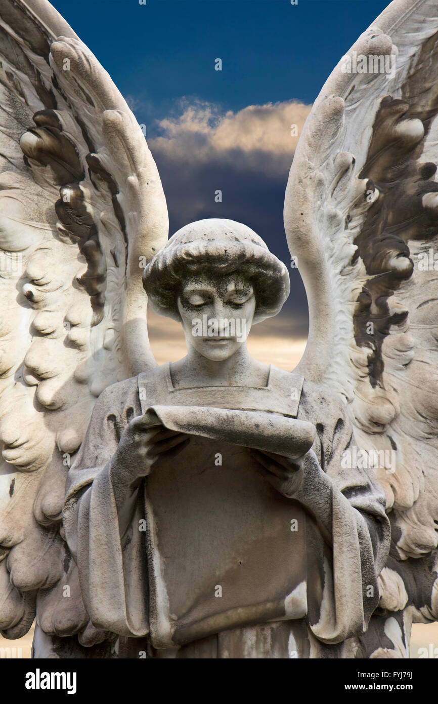 Statue of an angel reading a scroll with sunset landscape at the ...