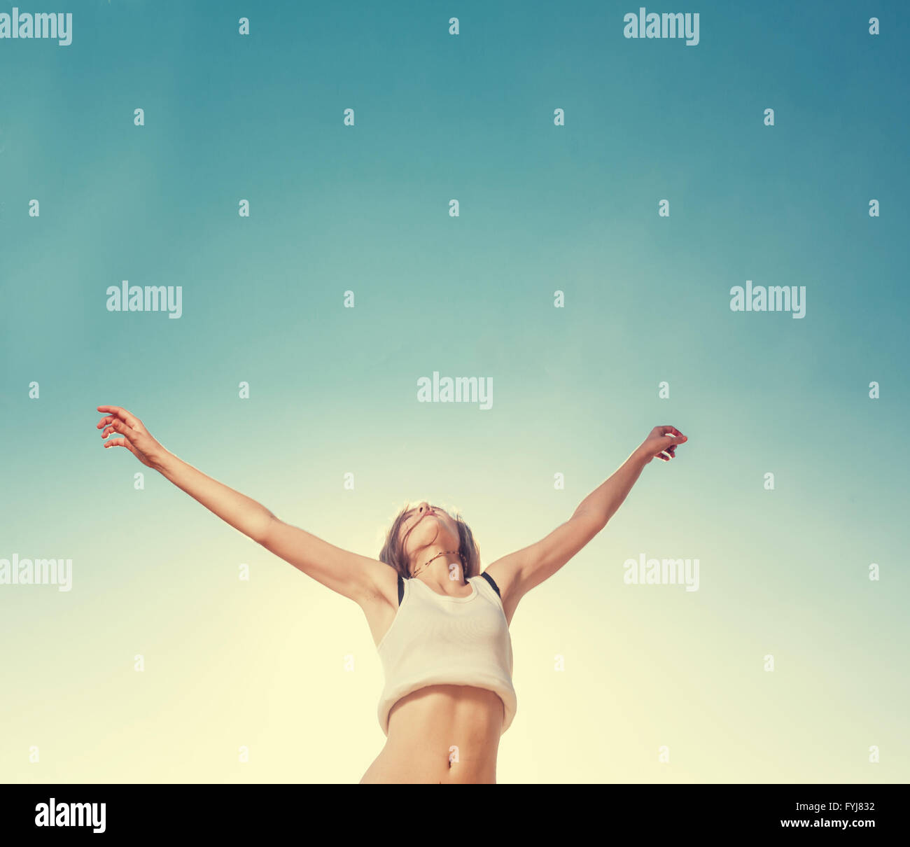 Blonde teenager girl jumping happy with the blue sky in the back Stock ...