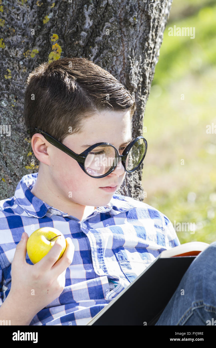Young boy reading a book in the woods with shallow depth of field and ...
