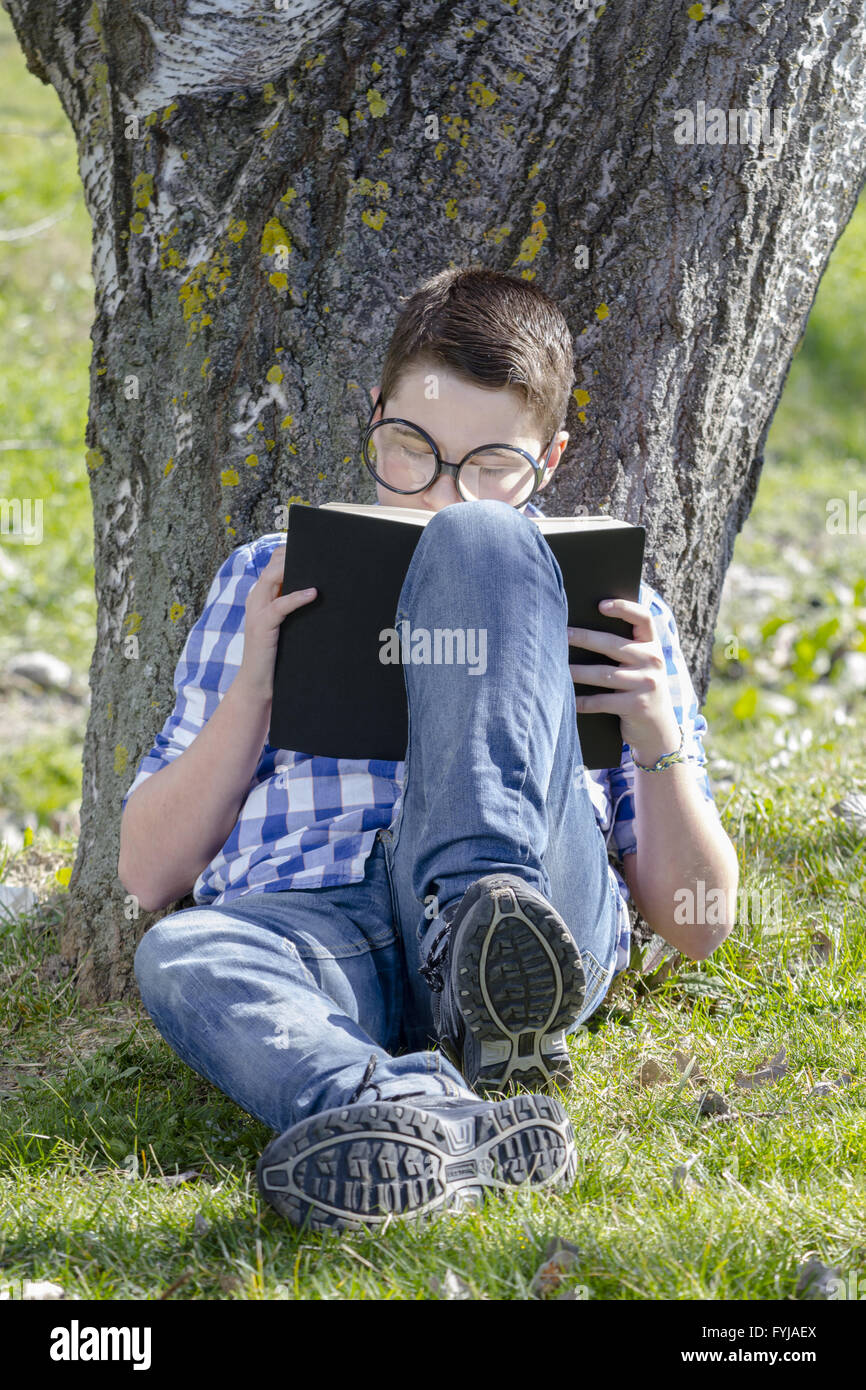 Young boy reading a book in the woods with shallow depth of field and ...
