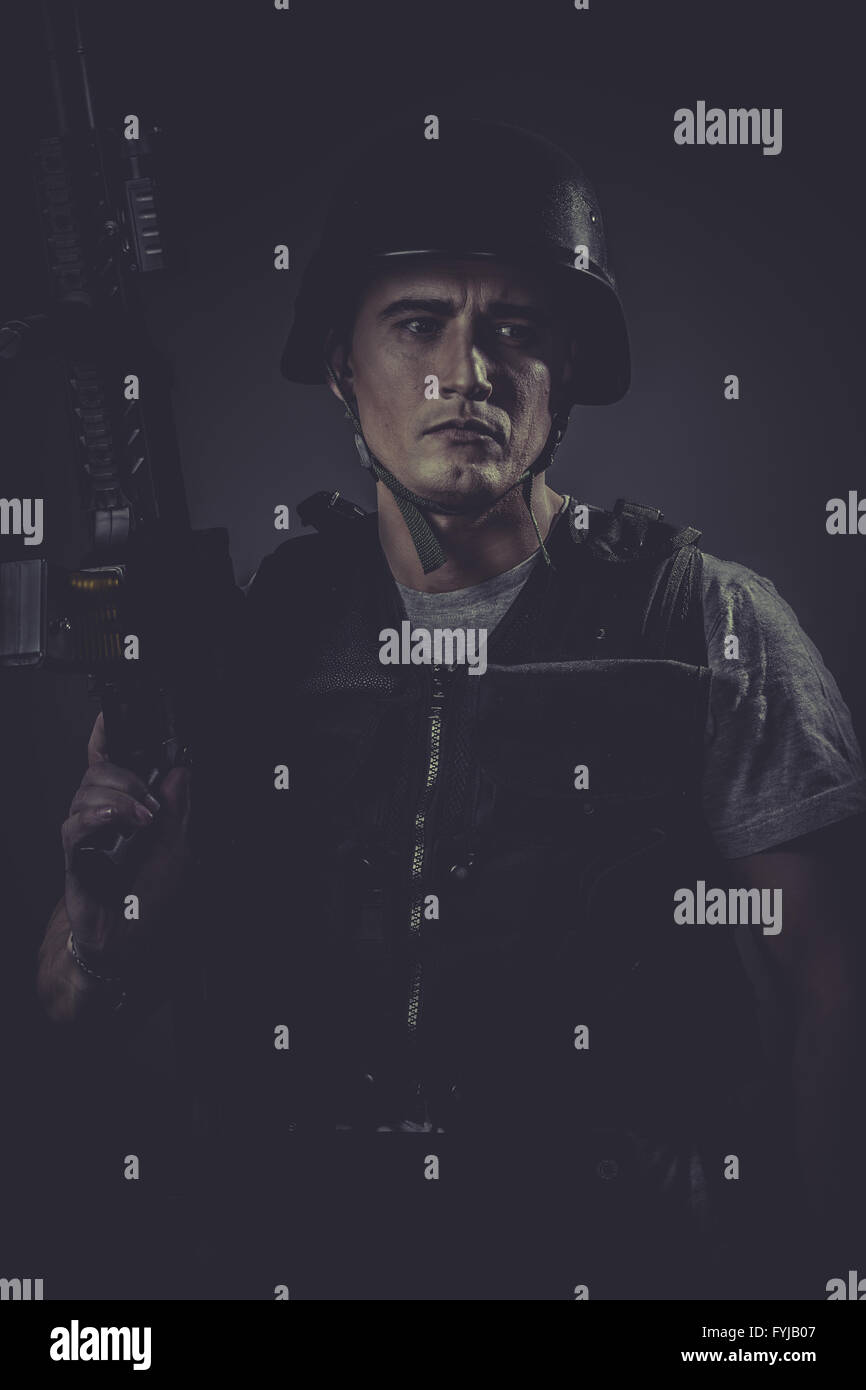 gamer wearing protective helmet aiming pistol ,black armor and machine ...