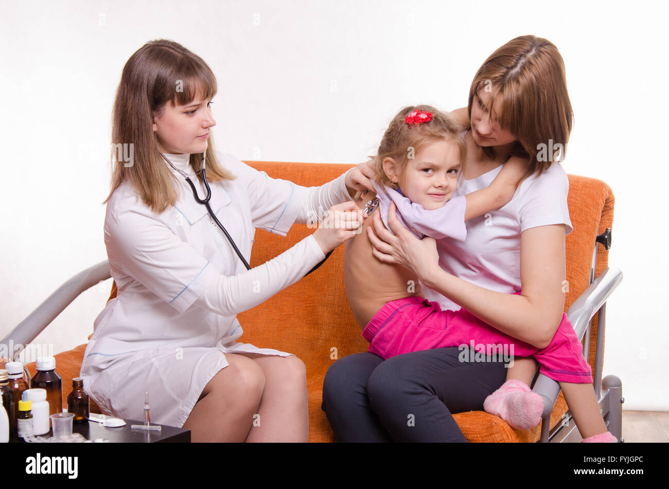Doctor listening stethoscope back at girl sitting in hands of mother ...