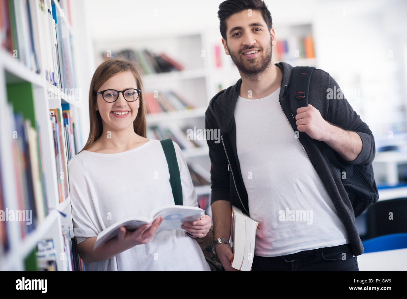 happy students couple in school library have discussion about book ...