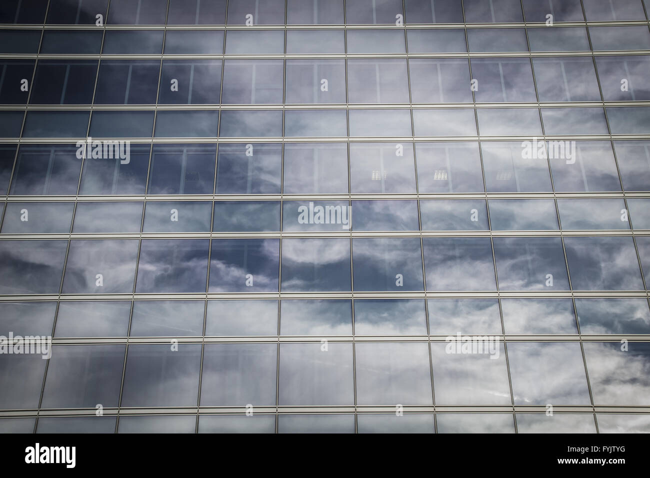 contemporary, skyscraper with glass facade and clouds reflected in ...