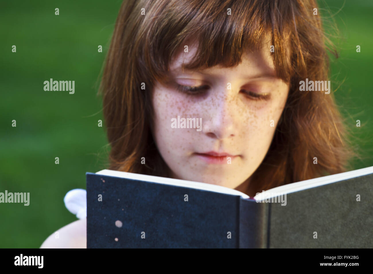 Young beautiful girl reading a book outdoor Stock Photo - Alamy