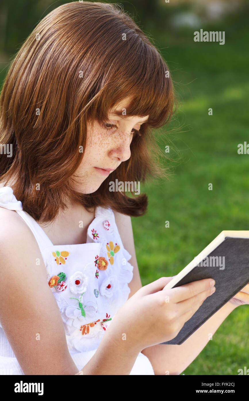 Young beautiful girl reading a book outdoor Stock Photo - Alamy
