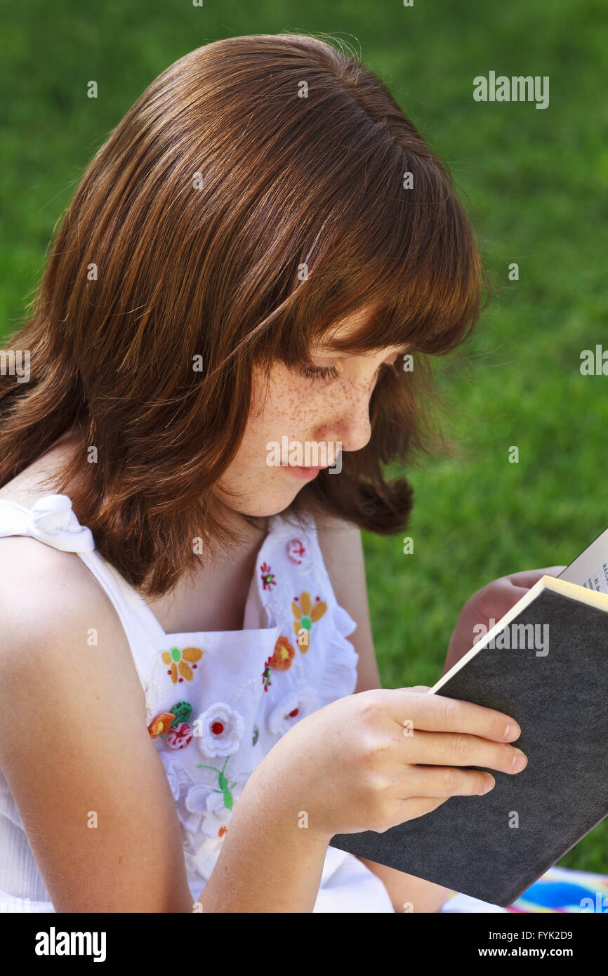 Young beautiful girl reading a book outdoor Stock Photo - Alamy