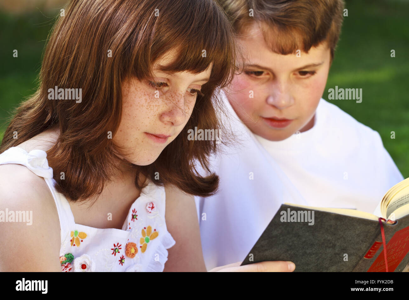 Portrait of cute kids reading books in natural environment Stock Photo ...