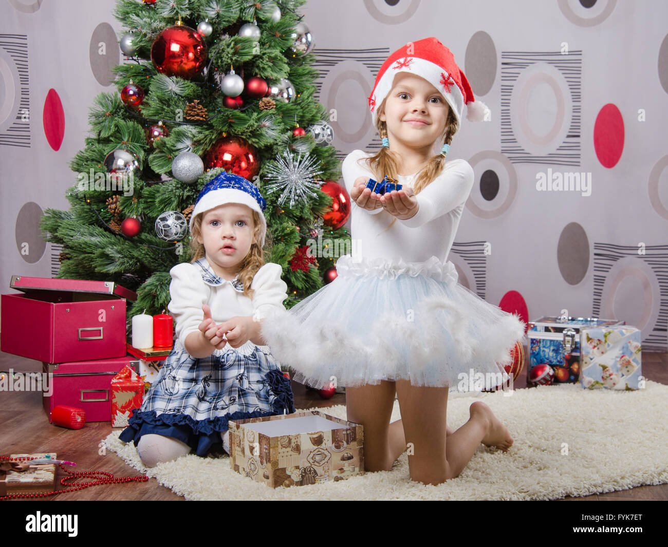 Two girls with small gifts at Christmas tree Stock Photo - Alamy