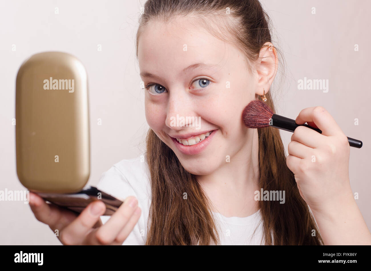 Twelve year old girl gets brush powder on cheek Stock Photo - Alamy