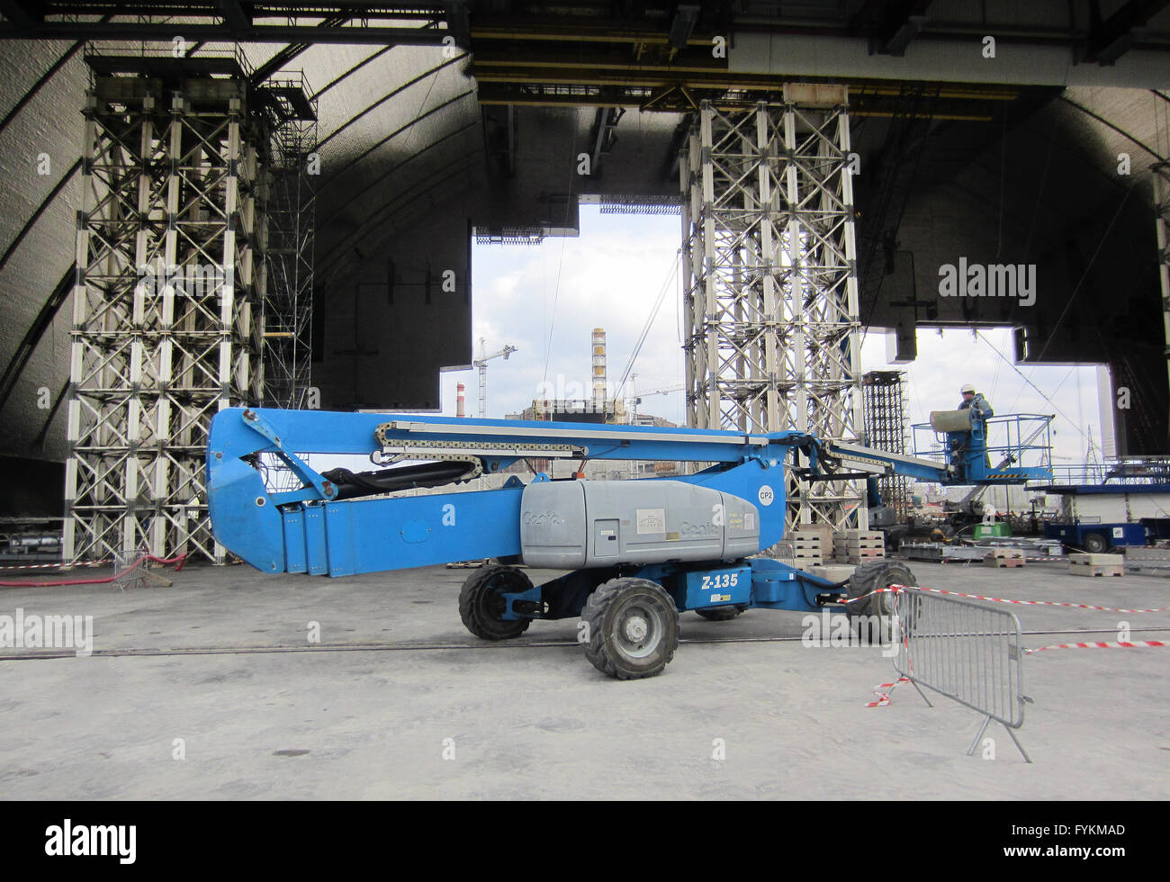 Workers stand underneath the stainless steel safe confinement casket ...