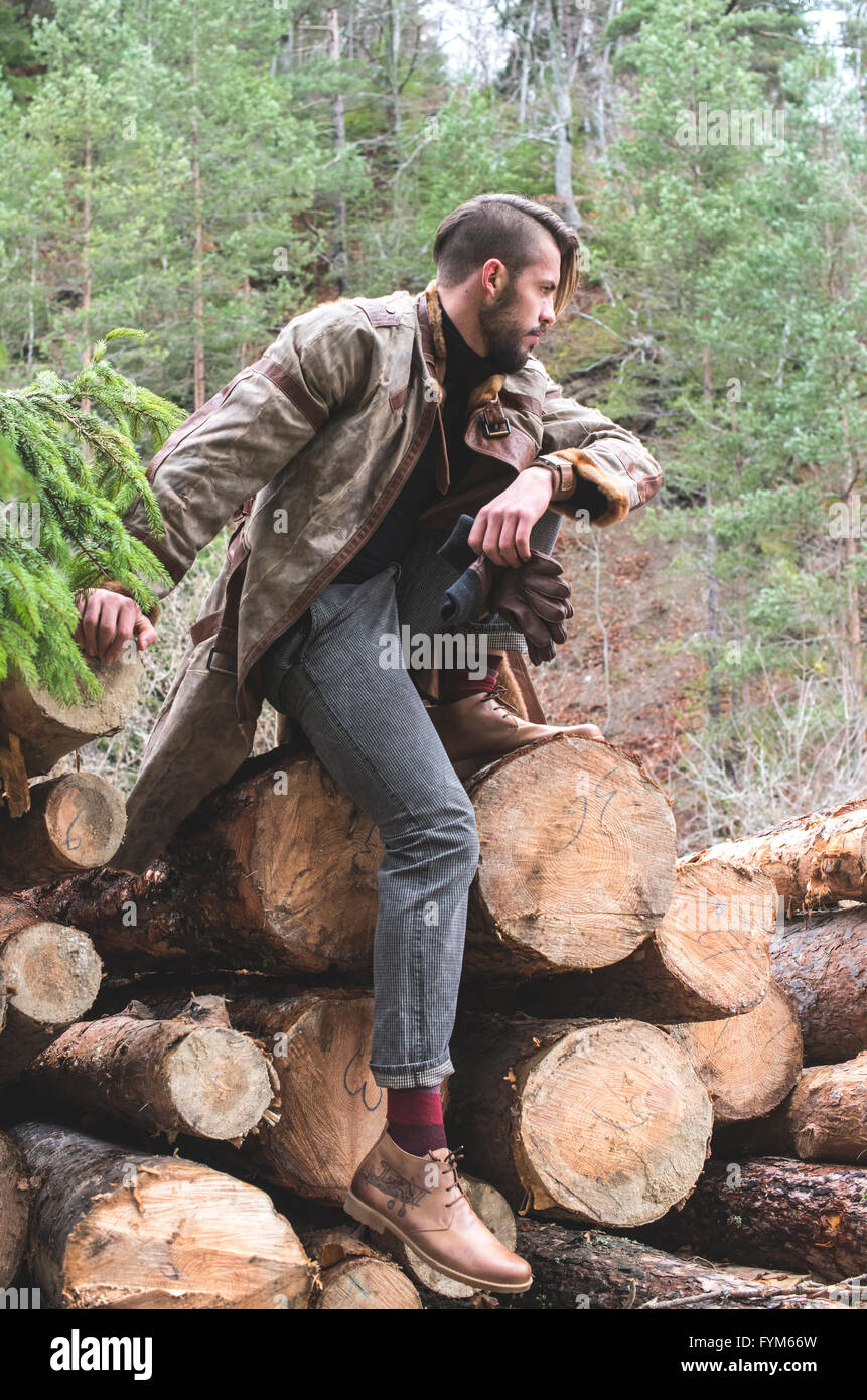Young men on logs in the forest. Leather and jeans. Outdoor fashion ...