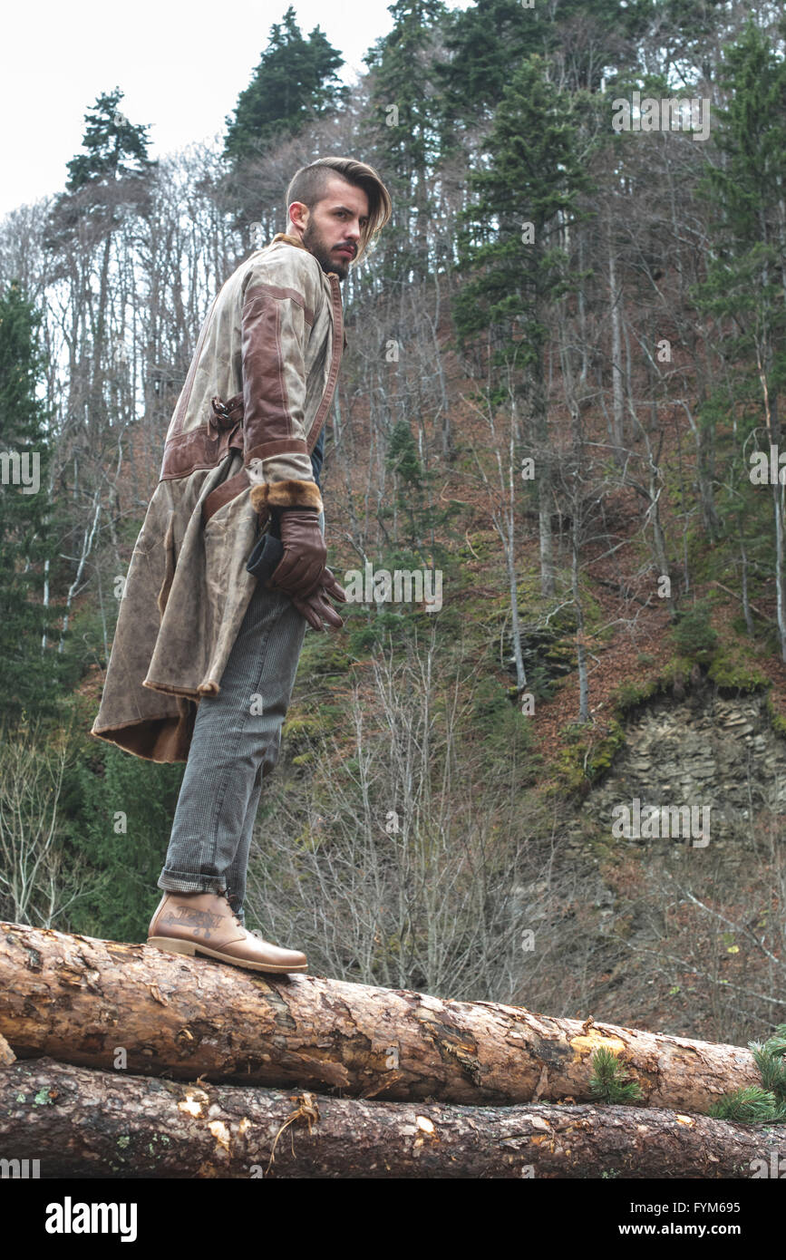 Young men on logs in the forest. Leather and jeans. Outdoor fashion ...