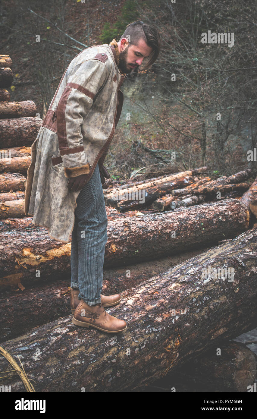 Young men on logs in the forest. Leather and jeans. Outdoor fashion ...