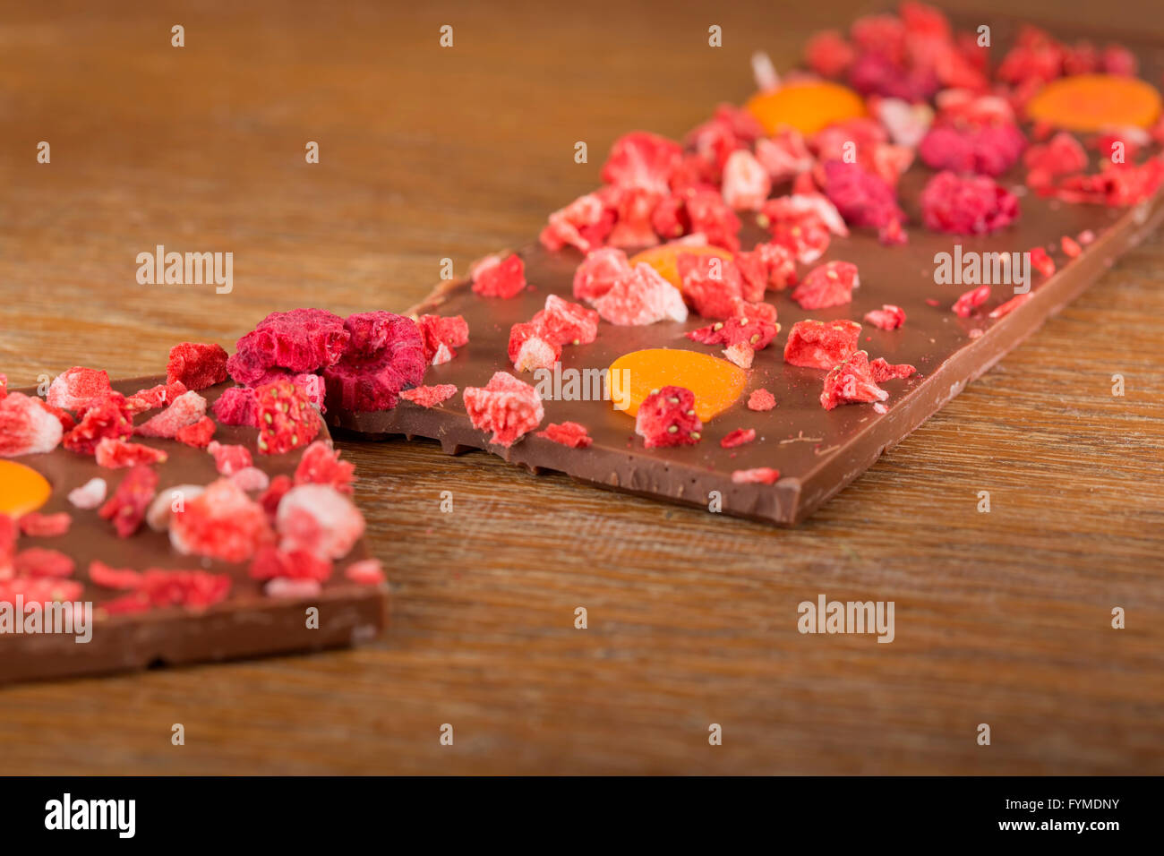 Orange, strawberry and raspberry milk chocolate over wooden background ...