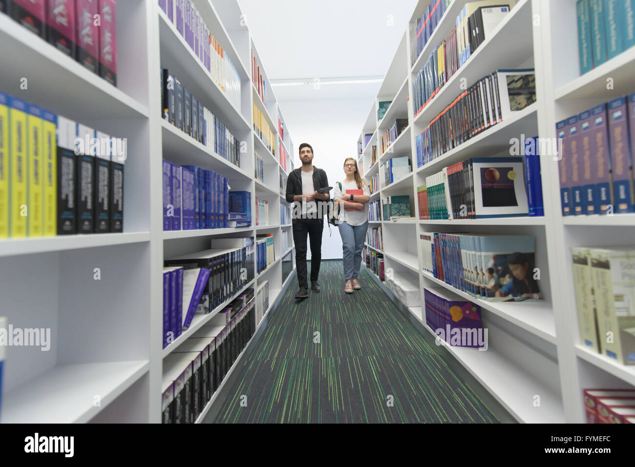 happy students group in school library selecting books to read and ...