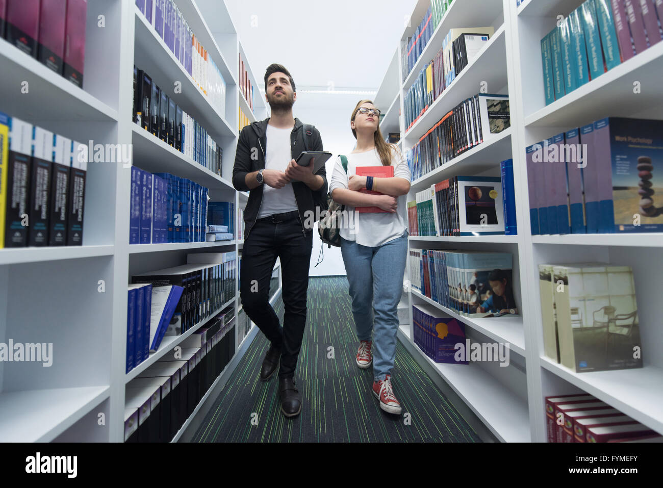 happy students group in school library selecting books to read and ...