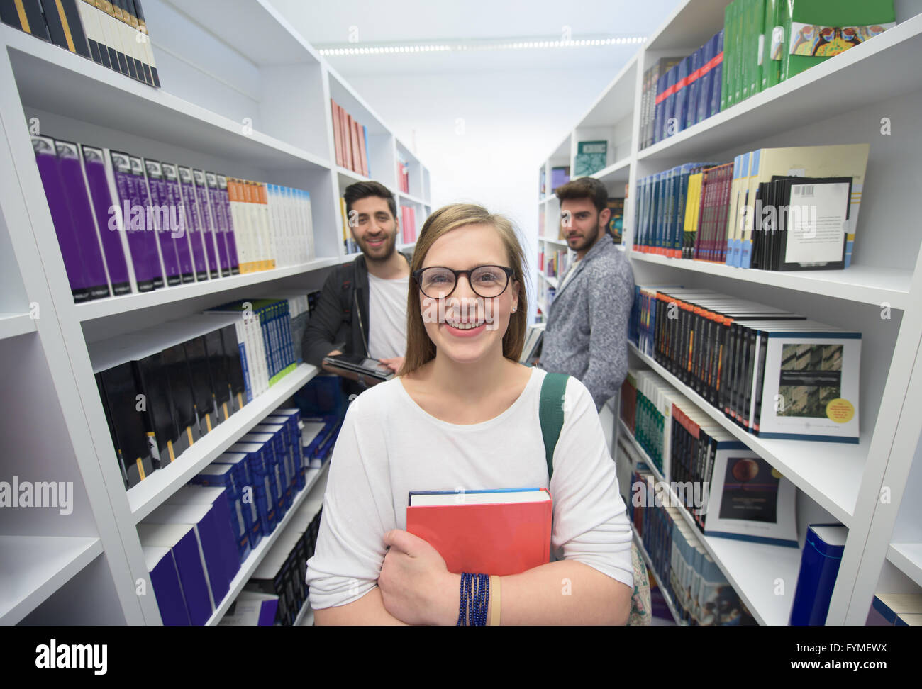 happy students group in school library selecting books to read and ...