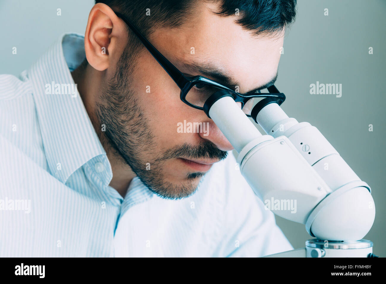 Young male doctor viewing through microscope Stock Photo - Alamy