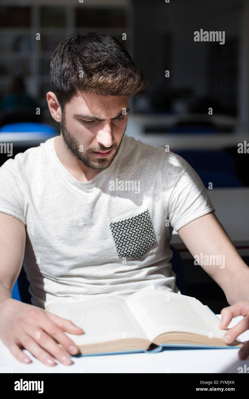 Student reading book in school library. Study lessons for exam. Hard ...