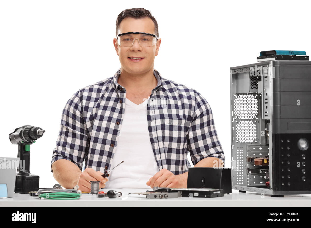 Cheerful PC technician sitting at a table and repairing a computer ...