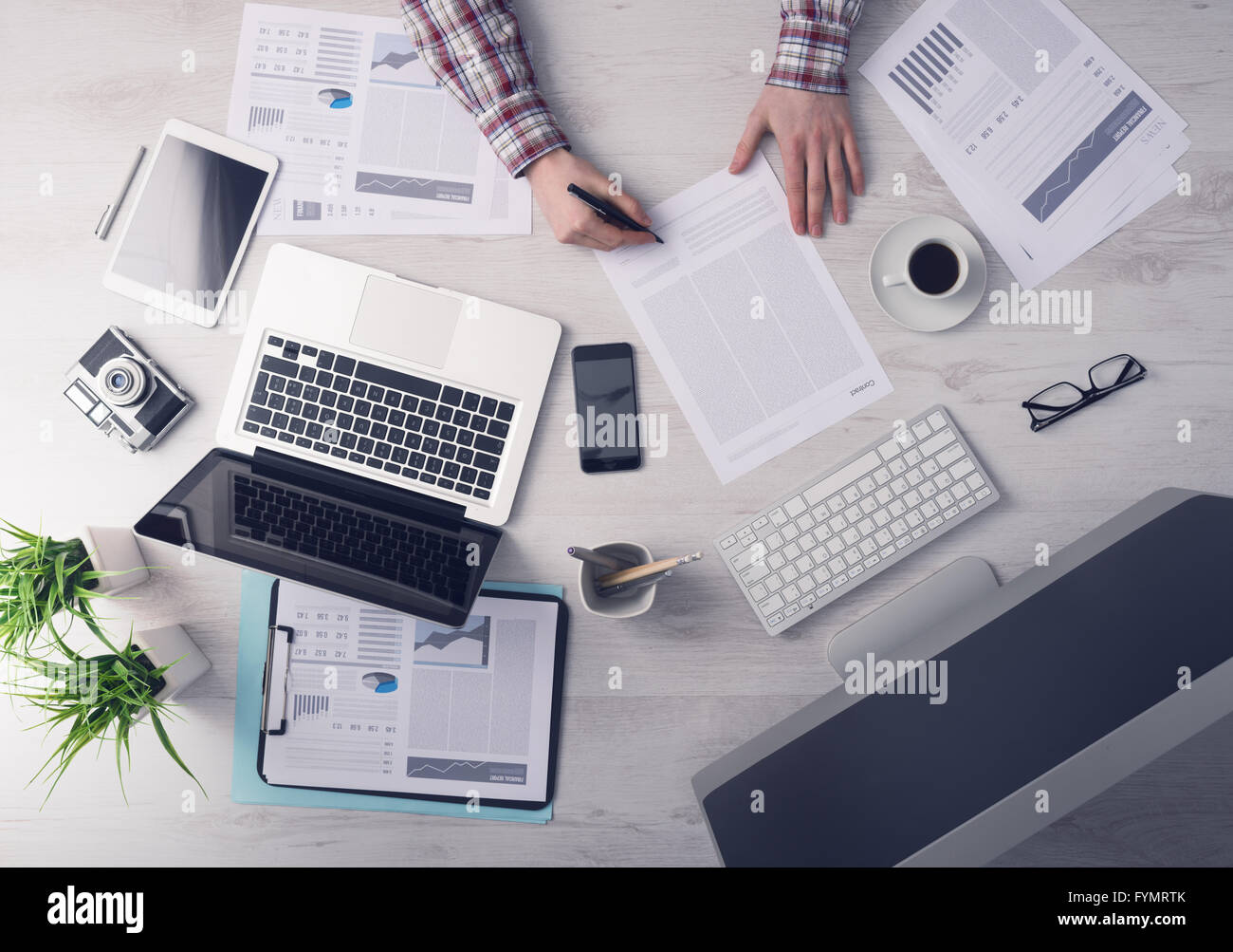Businessman working at office desk and signing a document, computers ...