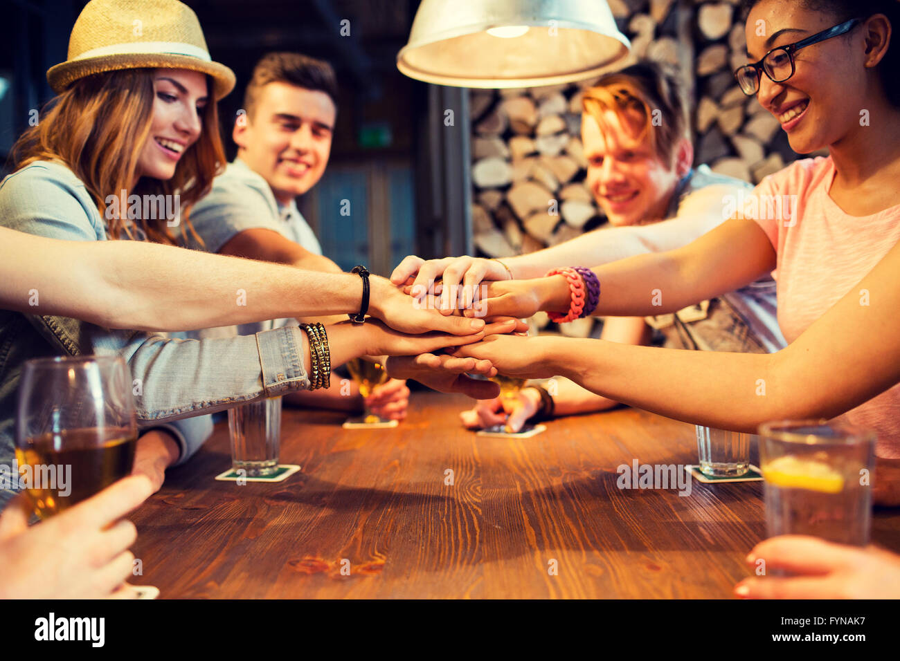 friends putting hands on top of each other at bar Stock Photo - Alamy
