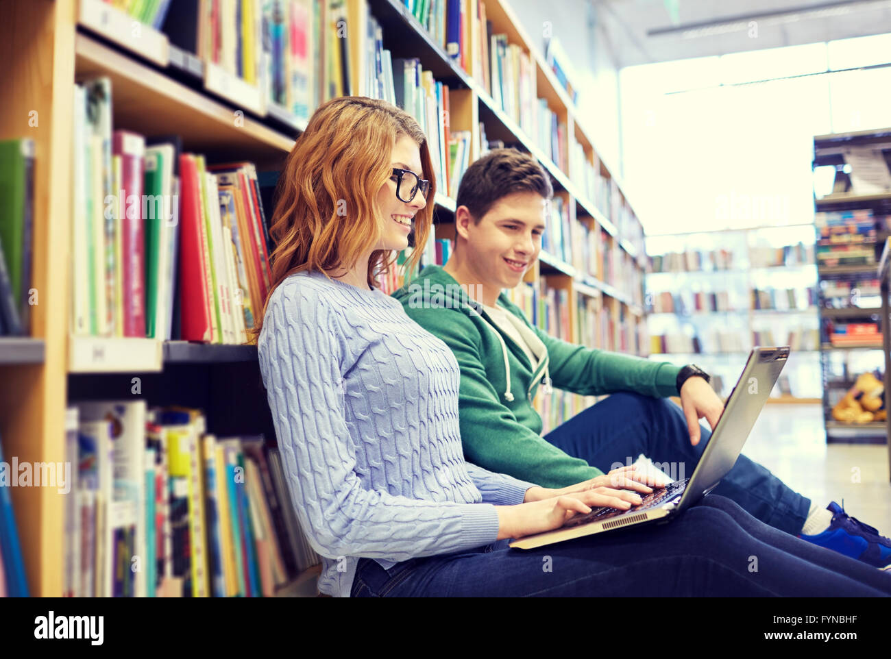 happy students with laptop in library Stock Photo - Alamy