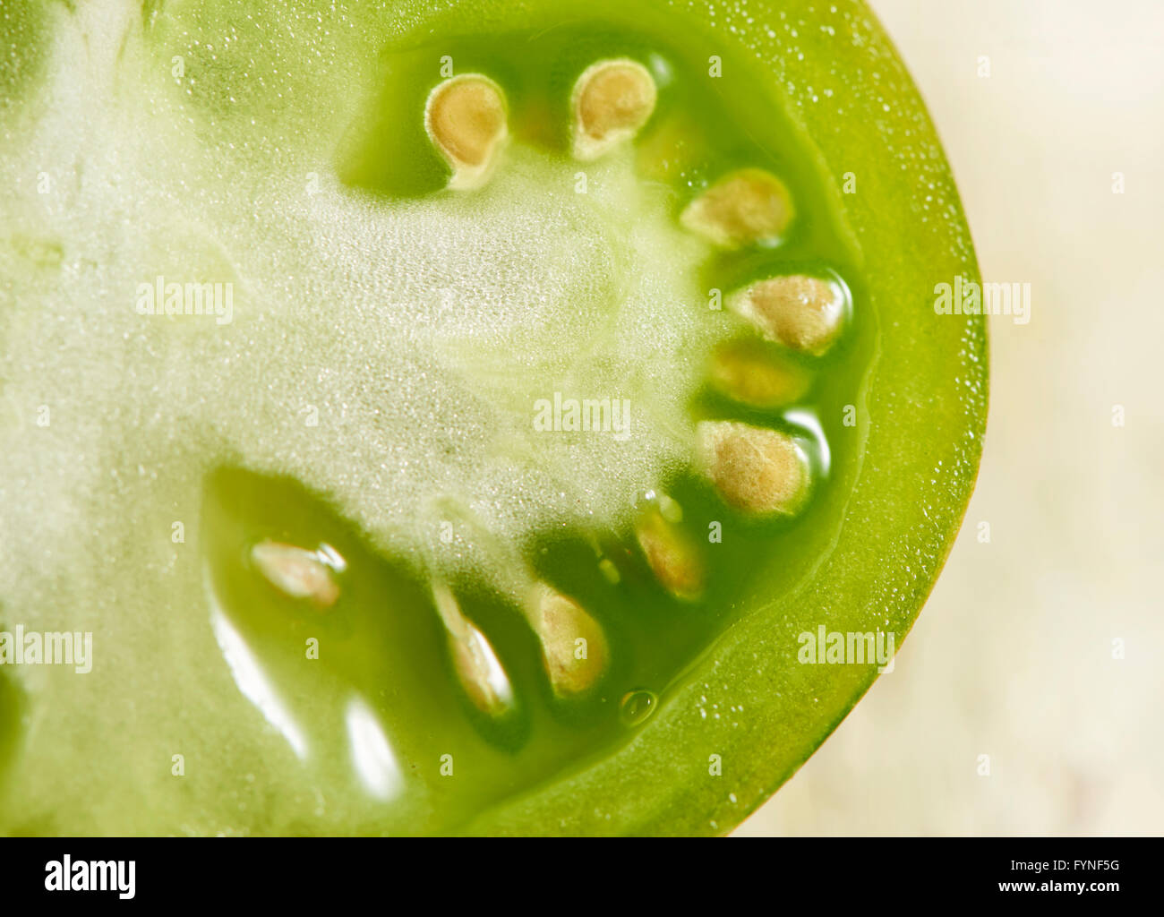 Close up macro of a sliced through fresh green tiger tomato showing the ...