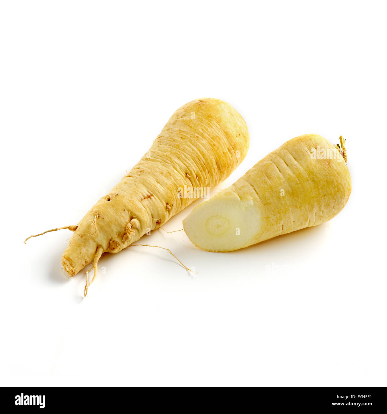 Whole and cut through diagonally halved fresh parsnips on a white ...