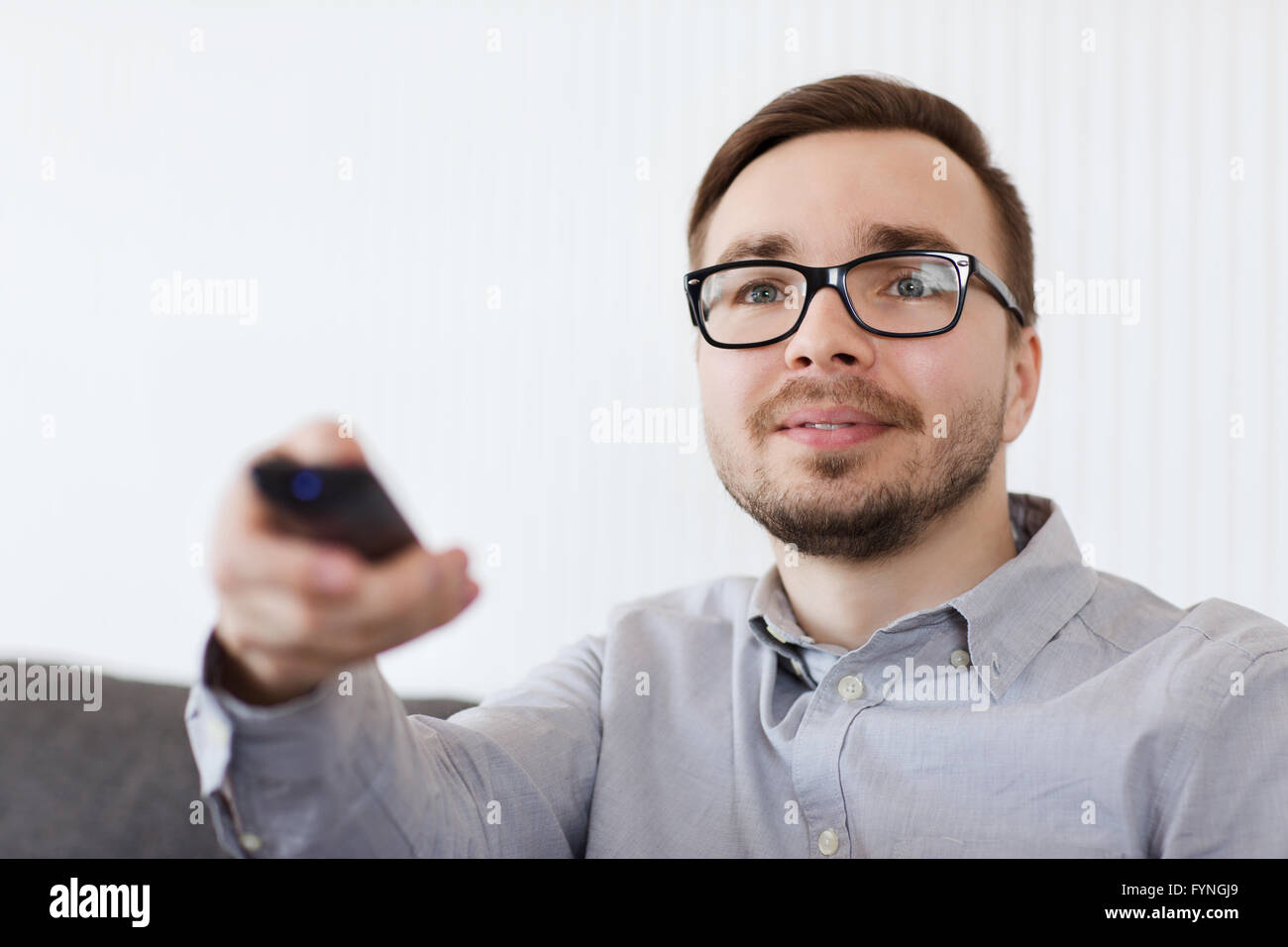 smiling man with tv remote control at home Stock Photo - Alamy