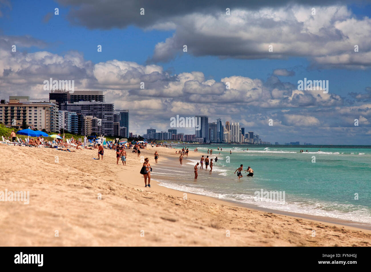 Scene of the crowded beach. People having fun, sunbathing and swimming ...