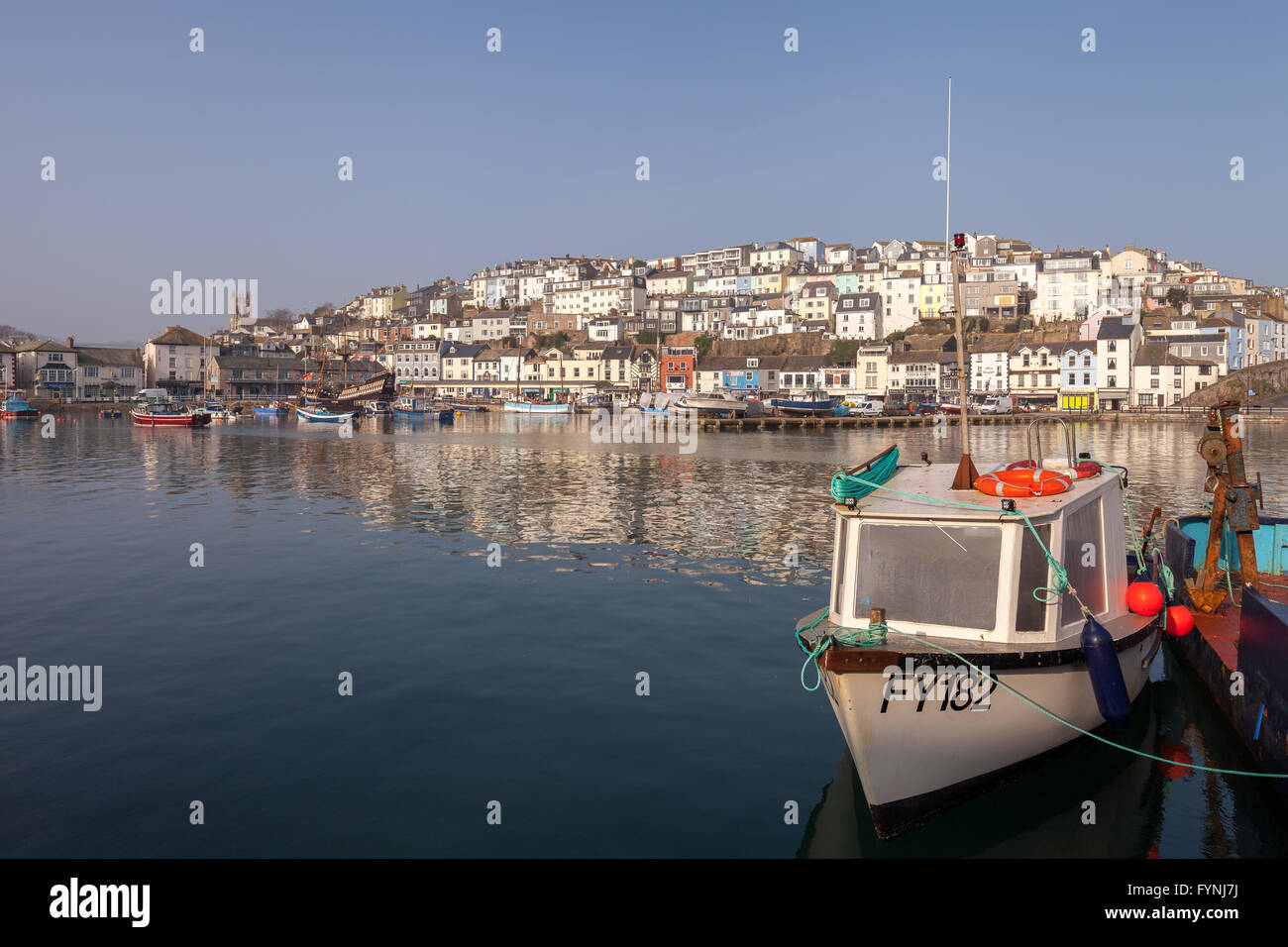 A postcard view of a boat at Brixham harbour. The morning sun shines on ...