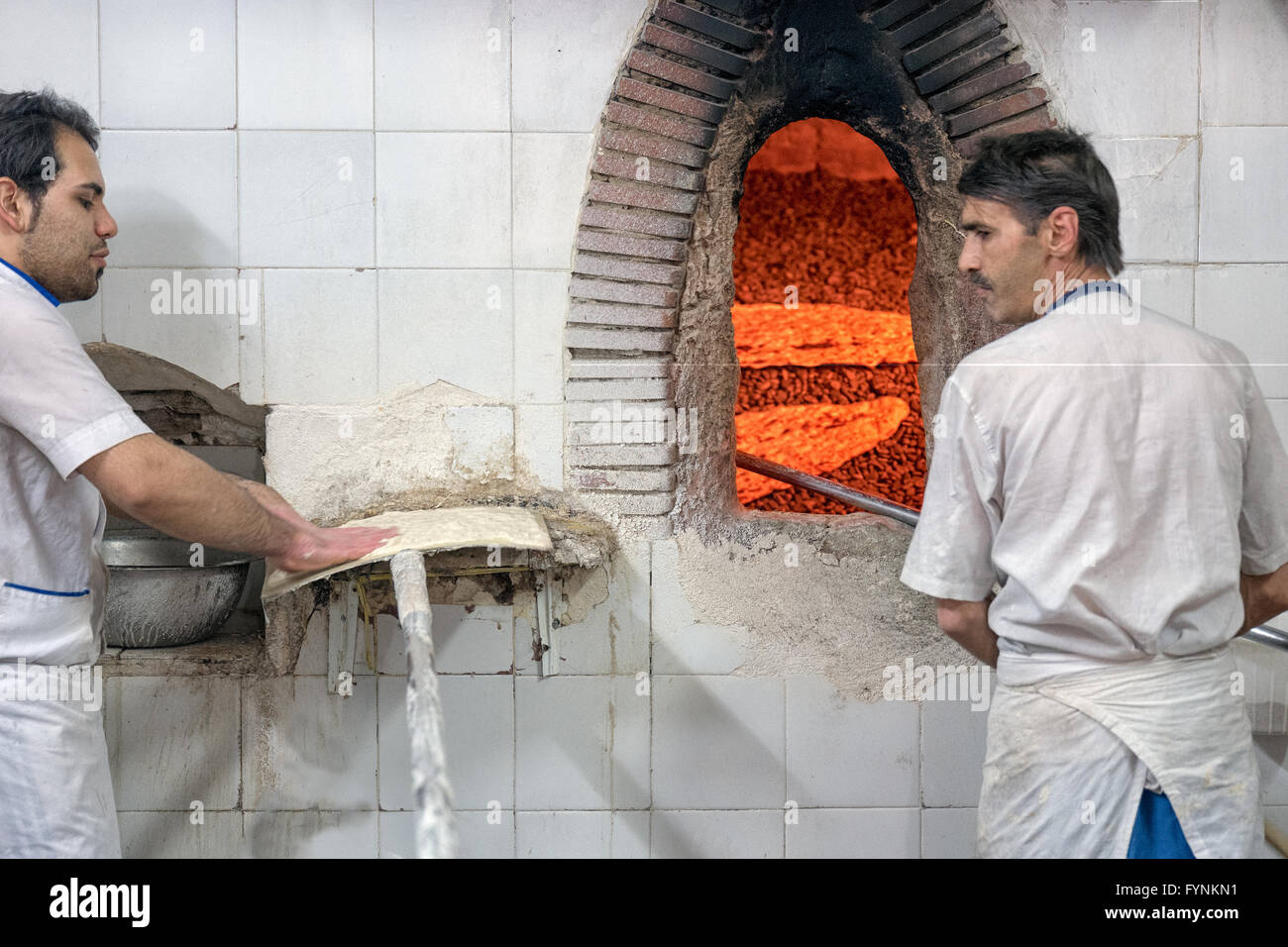 Iranian bakers making sangak bread that is cooked on hot stones in ...