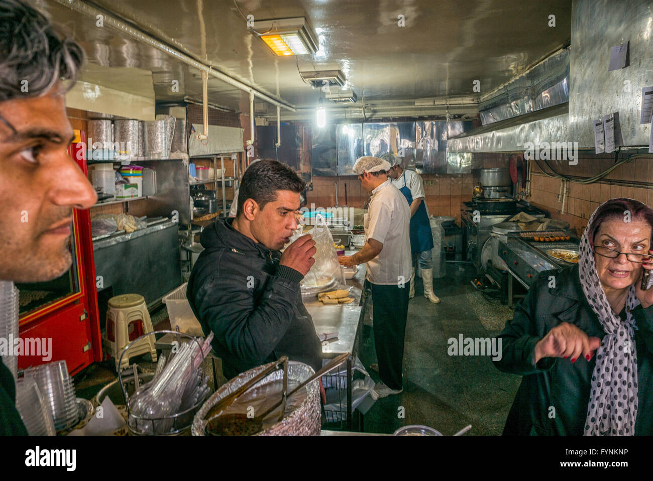 Chefs cook in a small restaurant kitchen with window on the street in ...
