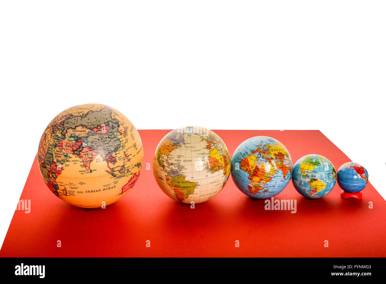 Globes of different sizes and color on a red background Stock Photo - Alamy