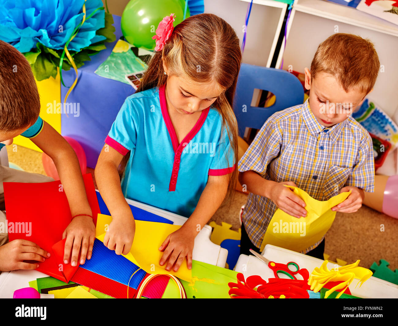 Kids holding colored paper on table in kindergarten Stock Photo - Alamy