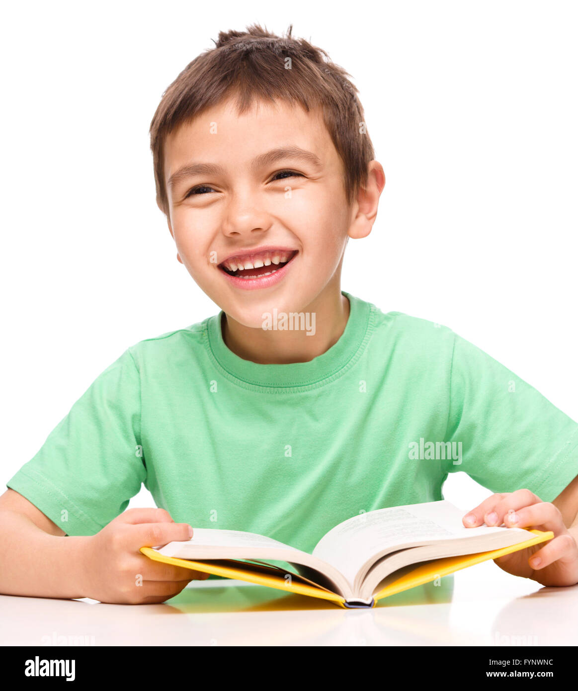 Cute little child plays with book while sitting at table, isolated over ...
