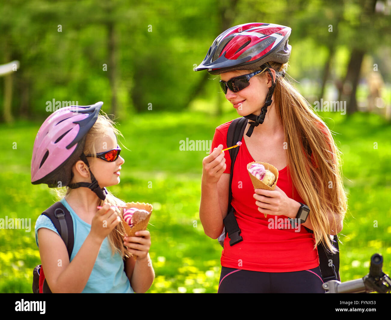 Bikes cycling girls with rucksack cycling eating ice cream cone in ...