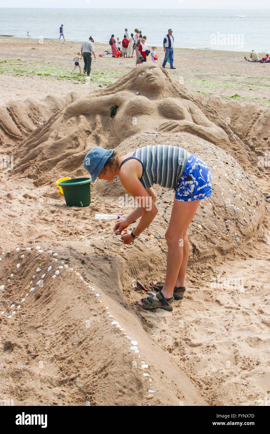 Making a sand sculpture of a mermaid on the beach at Exmouth, Devon ...