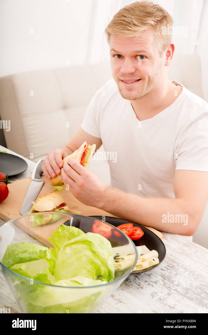 Young man eating a sandwich at home Stock Photo - Alamy