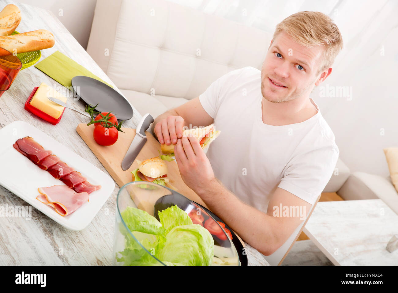 Young man eating a sandwich at home Stock Photo - Alamy