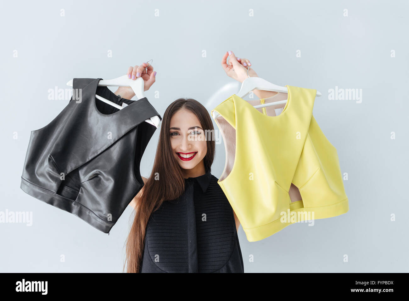 Smiling woman choosing between two jacket in store Stock Photo - Alamy