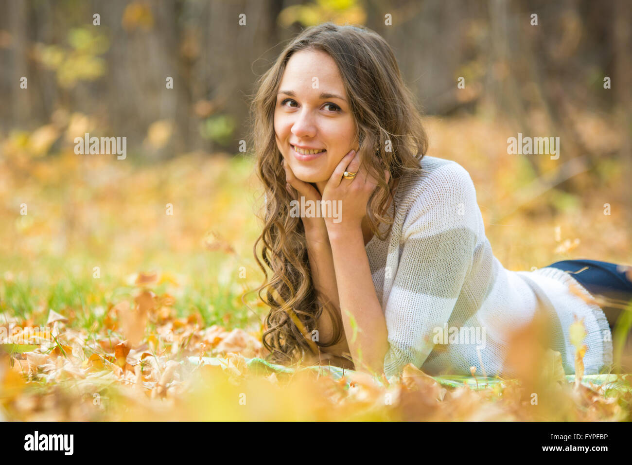 Young beautiful girl lies on the weave at a picnic in the autumn forest ...